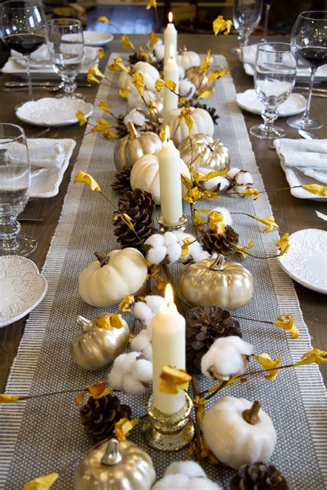 The Table Is Set With White Pumpkins And Pine Cones As Well As Candles