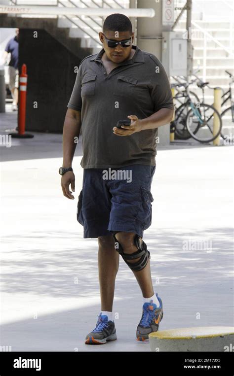 Wearing A Knee Brace Actor Omar Benson Miller Chats On His Cellphone