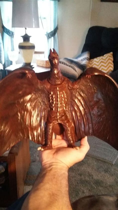 A Person Holding A Wooden Statue Of A Bird In Front Of A Living Room Window
