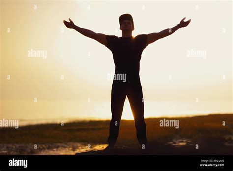 Silueta Del Hombre Con Sus Manos Levantadas En La Puesta De Sol En El