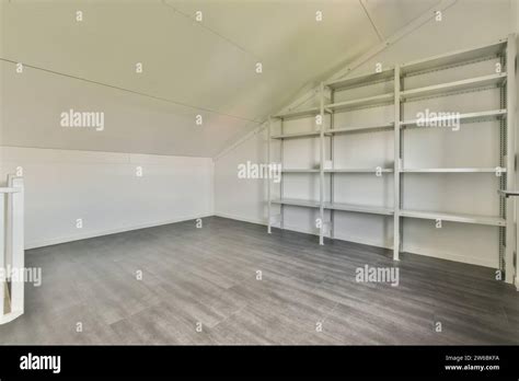 An Empty Attic Space With White Walls And Gray Flooring Featuring
