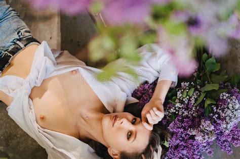 A Topless Blonde In A White Shirt And Jeans On The Floor With Lilac
