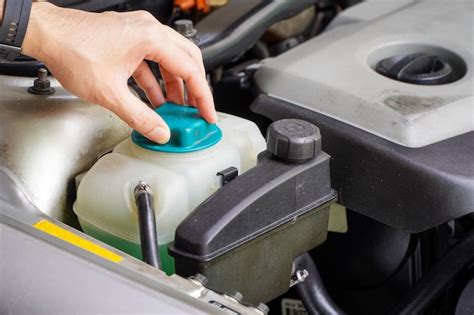 El mecánico inspecciona el tanque de expansión con anticongelante verde