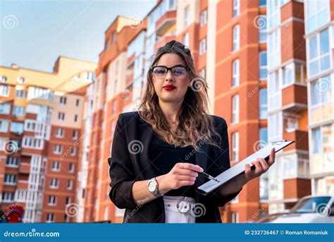 Attractive Young Estate Agent Who Holding Keys While Standing Against New Modern House At