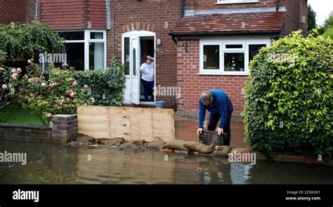 A Man Tries To Board Up His Drive To Prevent Rising Flood Water From
