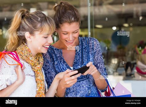 Beautiful Women Holding Shopping Bags Looking At Pictures Stock Photo
