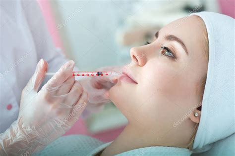 Manos del cosmetólogo haciendo inyección en la cara labios Mujer
