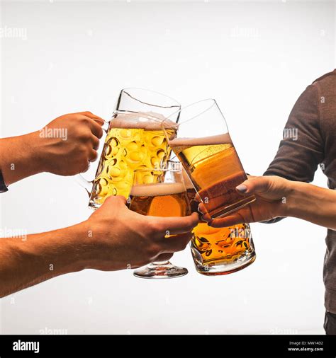Hands With Mugs Of Beer Toasting Creating Splash Isolated On White