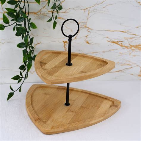 Two Tiered Wooden Trays With Metal Rings On Each One And A Plant In The