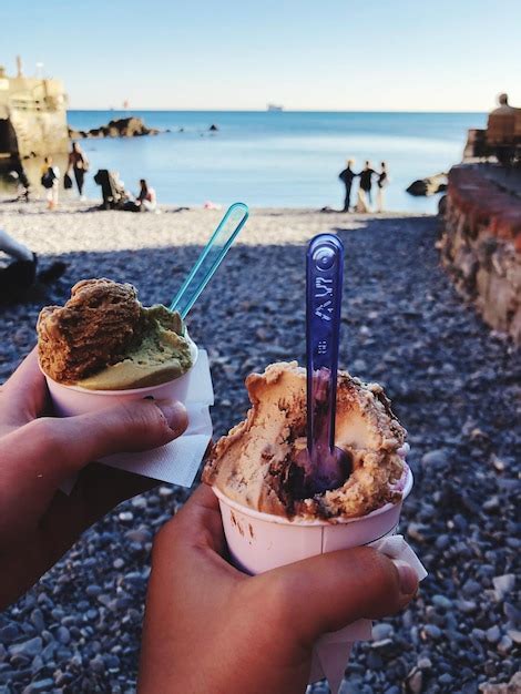 Premium Photo Close Up Of Cropped Hands Holding Ice Cream At Beach