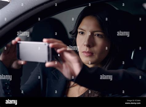 Attractive Serious Woman Taking A Selfie On Her Mobile Phone As She Waits In Her Car In The