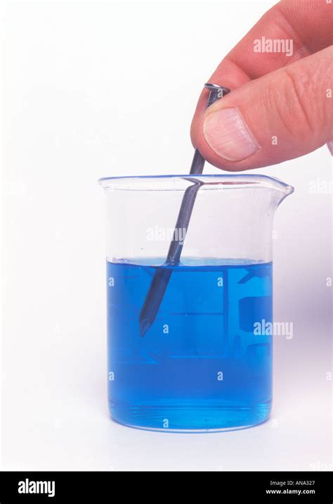 An Iron Nail Being Put Into A Beaker Of Copper Sulphate Solution In
