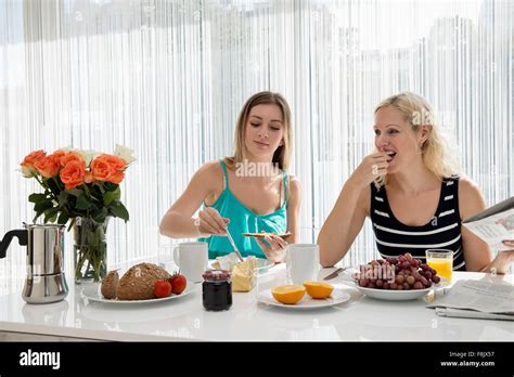Women Sitting At Dining Table Spreading Butter On Bread Eating A