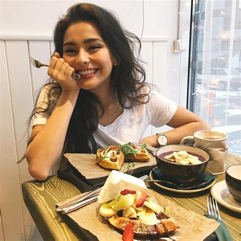 A Woman Sitting At A Table With Food In Front Of Her And Smiling For