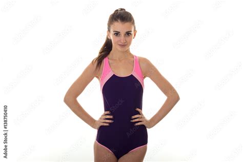 Beautiful Slim Girl In Body Swimsuit Looks Into The Camera And Keeps Her Hands On The Sides