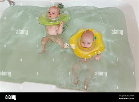 Newborn Twins Swimming In The Bath Or Bathtub Inflatable Circle Helps Them To Stay On The