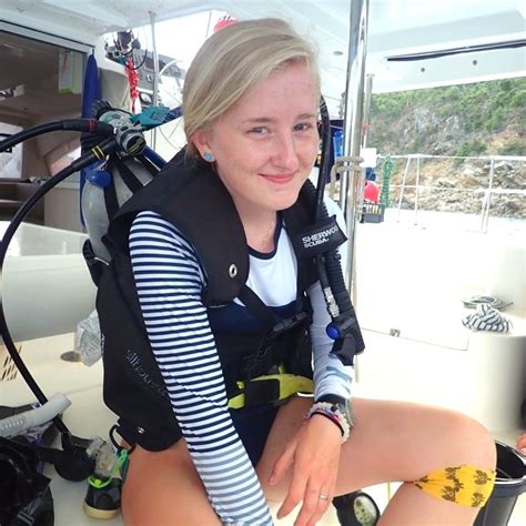 A Woman Sitting On The Back Of A Boat In Her Life Jacket And Diving Gear