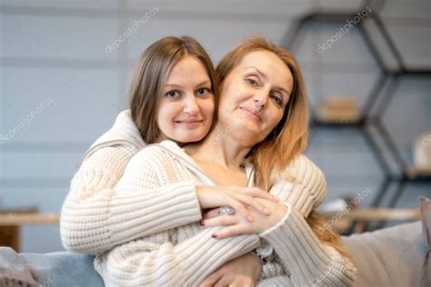 Hermosa familia de madre e hija juntas abrazándose y besándose en casa