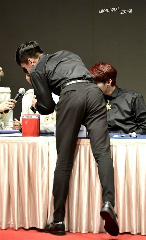 Two Men In Black Shirts And Pants Standing Over A Table