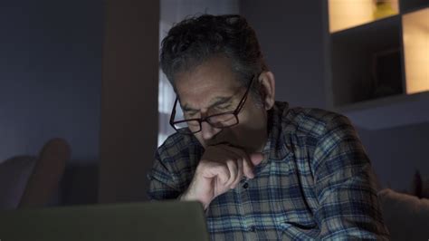 Tired Sleepy Old Man Looking At Laptop At Night The Sleepy Man Yawns