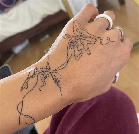 A Person With A Tattoo On Their Arm Holding A Cell Phone In The Other Hand