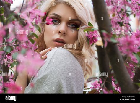 Beautiful Young Woman Enjoying Sunny Day In Park During Cherry Blossom Season On A Nice Spring