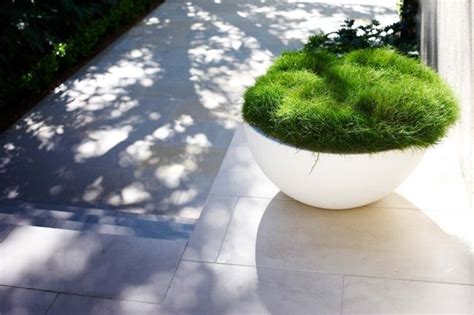 A White Planter Filled With Green Grass Sitting On Top Of A Cement