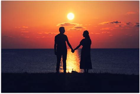 Poster Glanzend Silhouet Van Koppel Hand In Hand Bij De Zee Tijdens