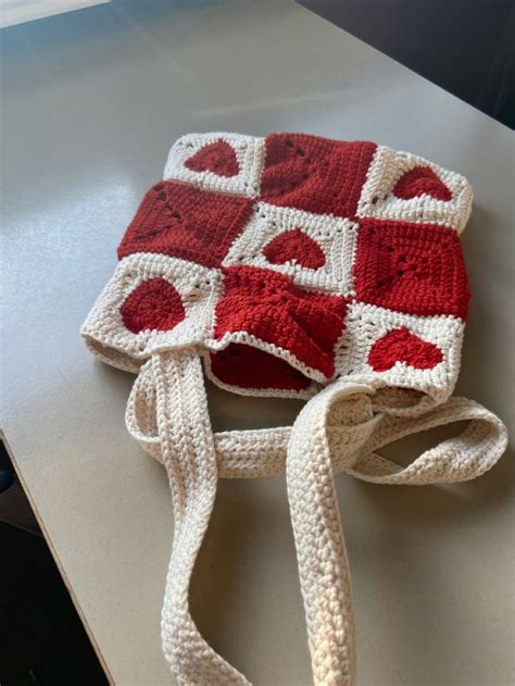A Red And White Crocheted Bag Sitting On Top Of A Table