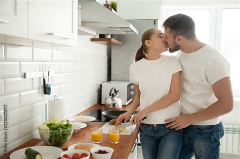 Romantic Young Couple Kissing In Kitchen While Cooking Breakfast Together Millennial Lovers