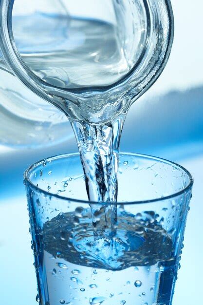Premium Photo Water Pouring From A Jug Into A Glass On Blue