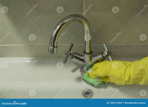 Hand In Yellow Glove With Sponge Cleaning White Sink Stock Photo