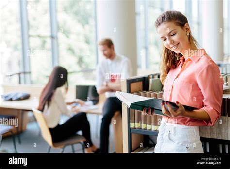 Beautiful Woman Reading A Book In A Library And Thinking Stock Photo