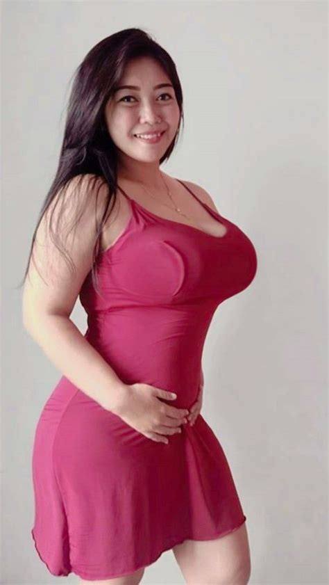 A Woman In A Short Pink Dress Posing For The Camera With Her Hands On
