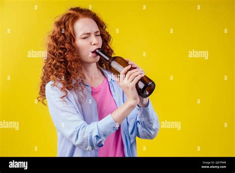 Curly Redhead Ginger Woman Drinking Beer And Feeling Bad Mood In Csudio Yellow Background Stock