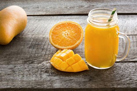 Zumo Del Mango Y De Naranja Y Rebanada De Naranja En La Tabla De Madera