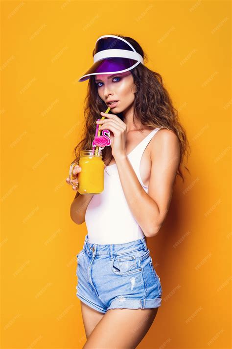 Premium Photo Sexy Woman In White Swimsuit And Blue Jeans Shorts Trendy Visor Holding Glass
