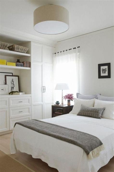 A Bedroom With White Walls And Wood Flooring Has A Bed Dressers And