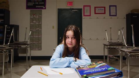 Young Brunette Girl Frustrated And Bored Sitting At Desk In Classroom During Detention Clipstock