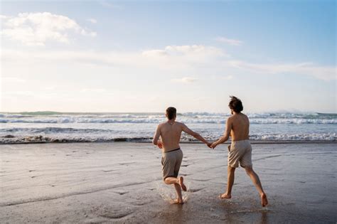 Hombres Gay De Tiro Completo Tomados De La Mano En La Playa Foto Gratis