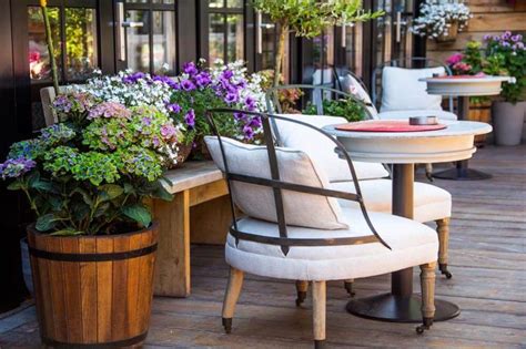 An Outdoor Patio With Potted Plants And Chairs On The Wooden Flooring