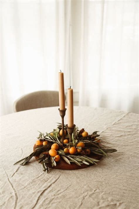 Two Candles Sitting On Top Of A Table With Oranges