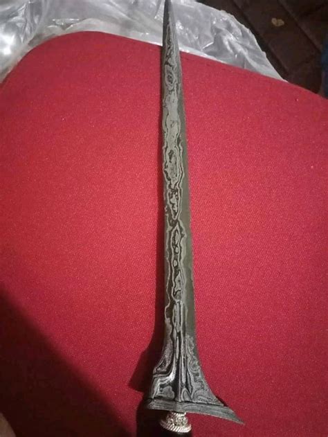 A Large Metal Knife Sitting On Top Of A Red Cushion