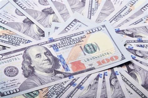 Un billete de cien dólares está encima de una pila de billetes de 100