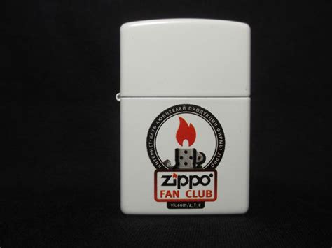A White Zippo Lighter Sitting On Top Of A Black Table Next To A Cup