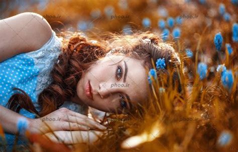 عکس زیبا دختر آبی پوش دراز کشیده به پهلو روی چمنزار و گل های کوچک آبی عکس با کیفیت و تصاویر