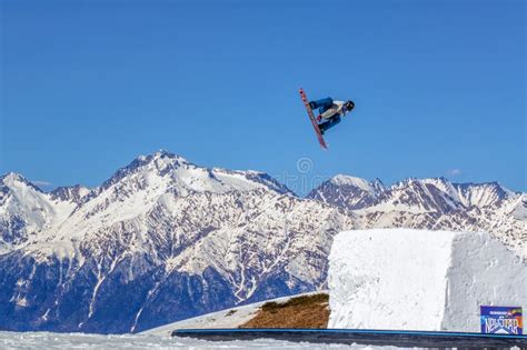 Um Voo Masculino Do Cavaleiro Do Snowboard De Um Salto De Esqui No