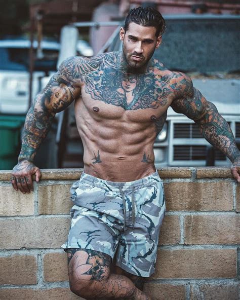 A Shirtless Man Leaning Against A Brick Wall With His Arms And Legs