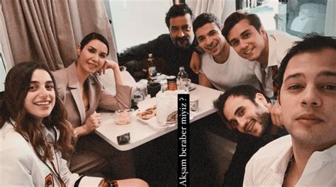A Group Of People Sitting At A Table With Food And Drinks In Front Of Them