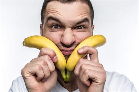 Premium Photo Man In White Shirt Is Holding Two Bananas Close To His Face